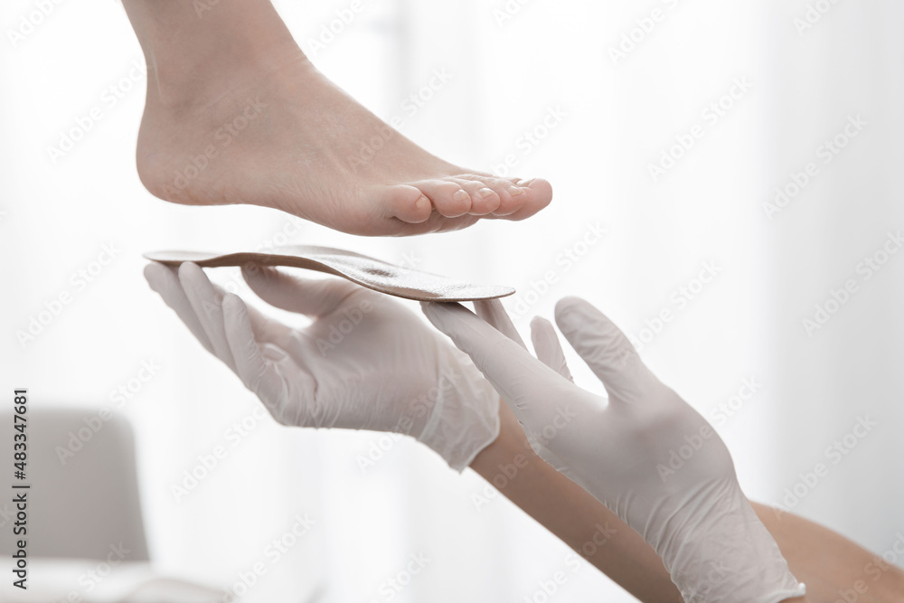 Orthopedic insole on a white background. Hands in rubber gloves hold an ...