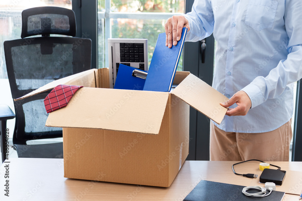 Cropped shot of a businessman leaving work putting his belongings in a ...