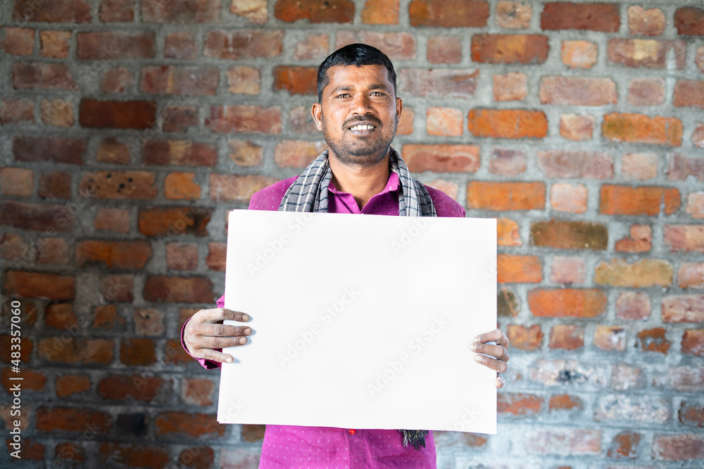 Smiling Construction worker holding empty sign board at site by looking ...