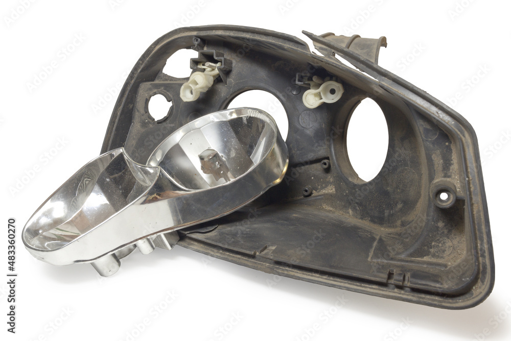 parts of disassembled headlight. cracked black plastic housing and ...