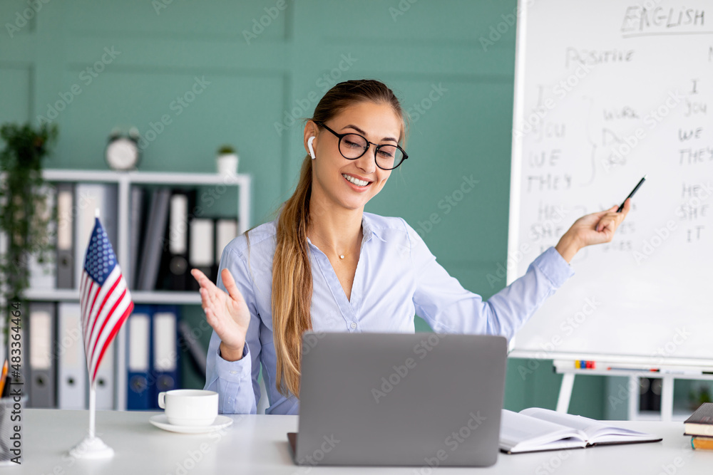 Happy young teacher conducting English lesson on web, using laptop ...
