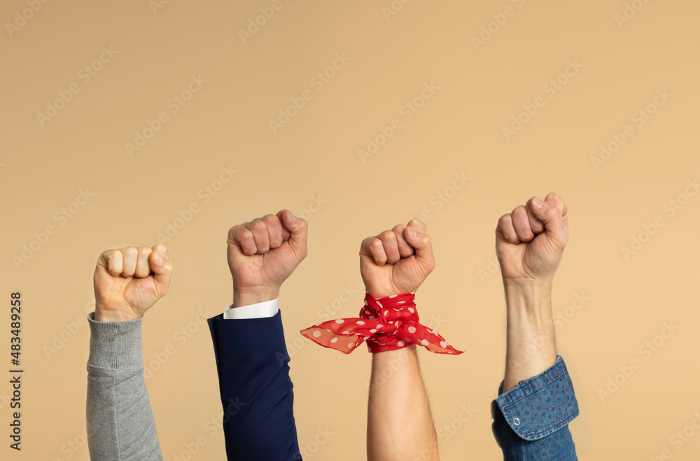 Four male hands on a beige background showing a fist, symbol of the ...