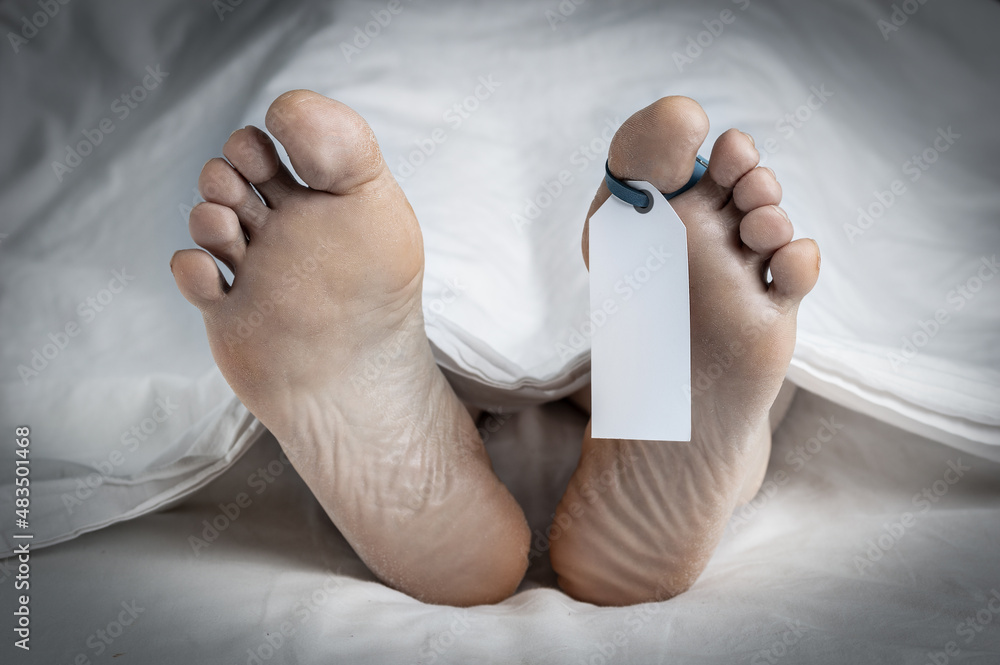 Close-up of the feet of a corpse covered in a sheet; with a blank tag ...