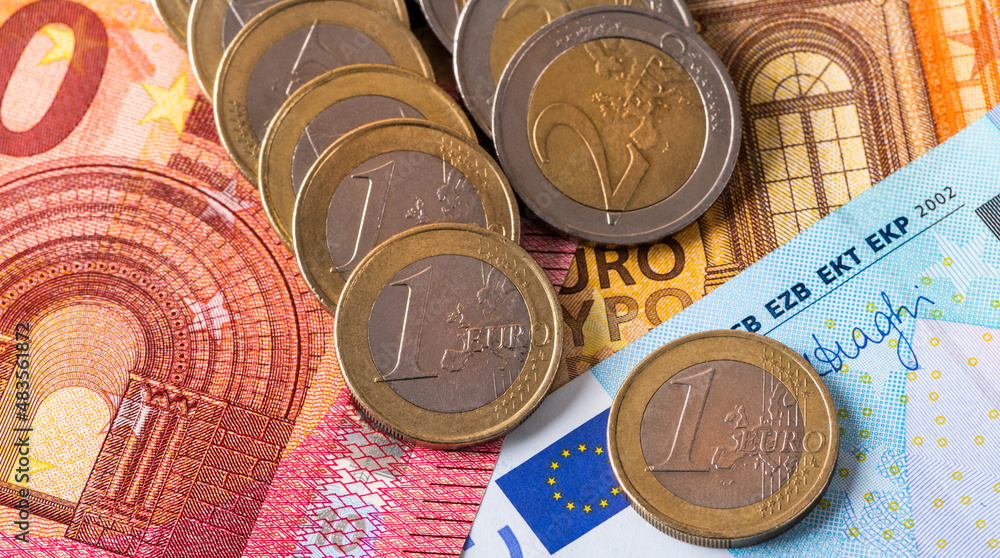 Coins in denominations of 1 and 2 euros against the background of euro ...