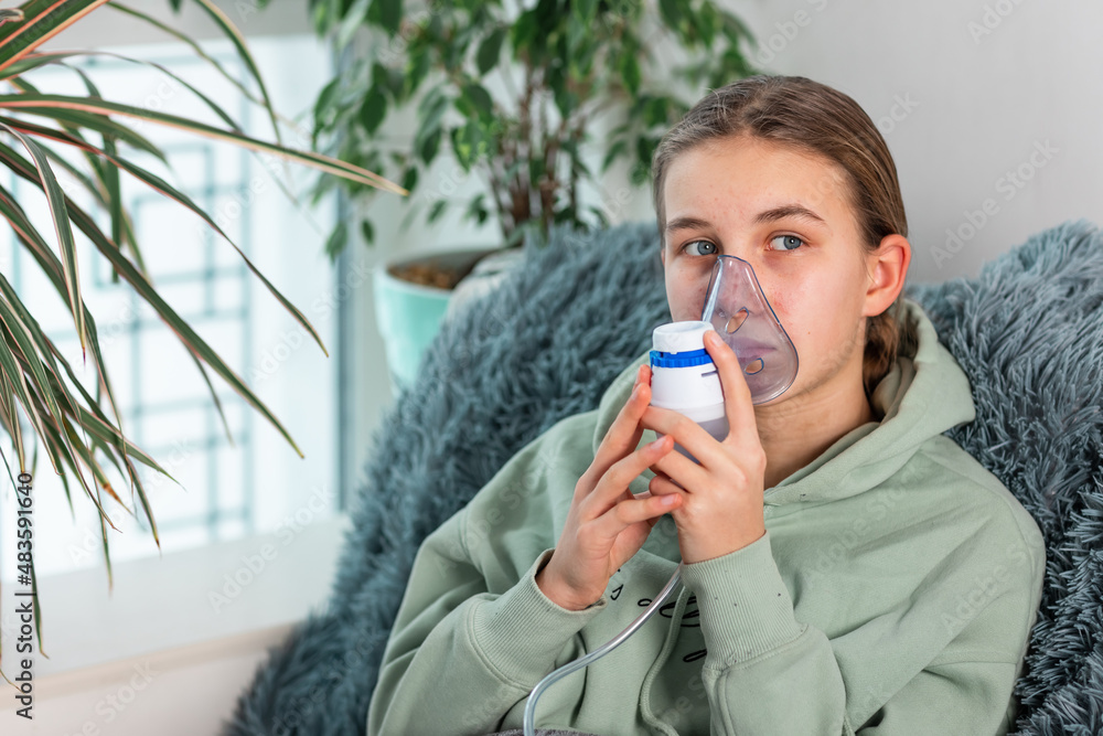 Teenage girl makes inhalation with a nebulizer equipment. Sick child ...