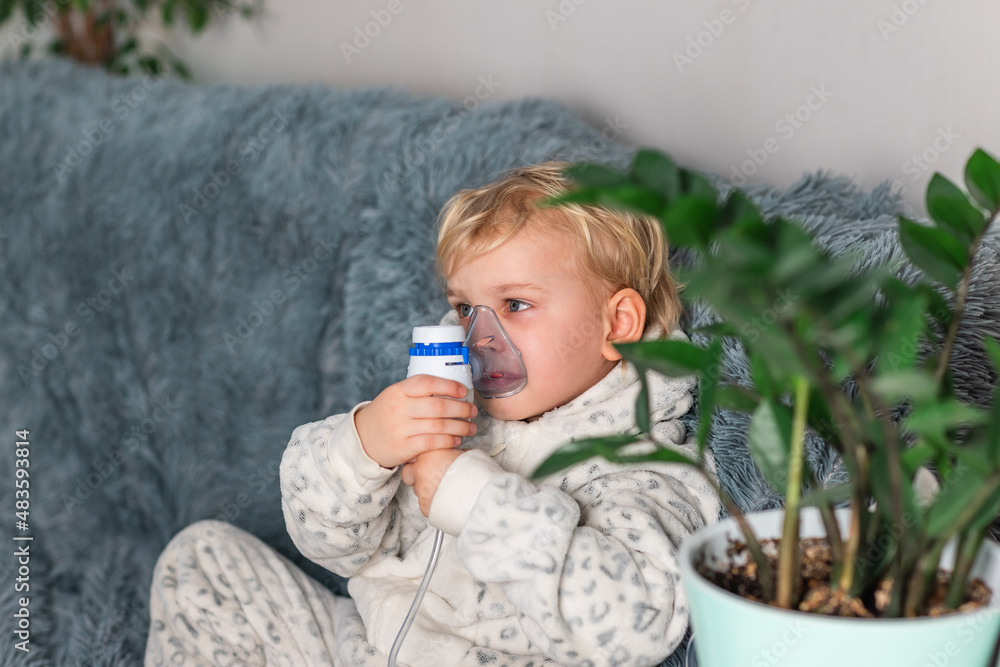 Cute baby boy makes inhalation with a nebulizer equipment. Sick child ...