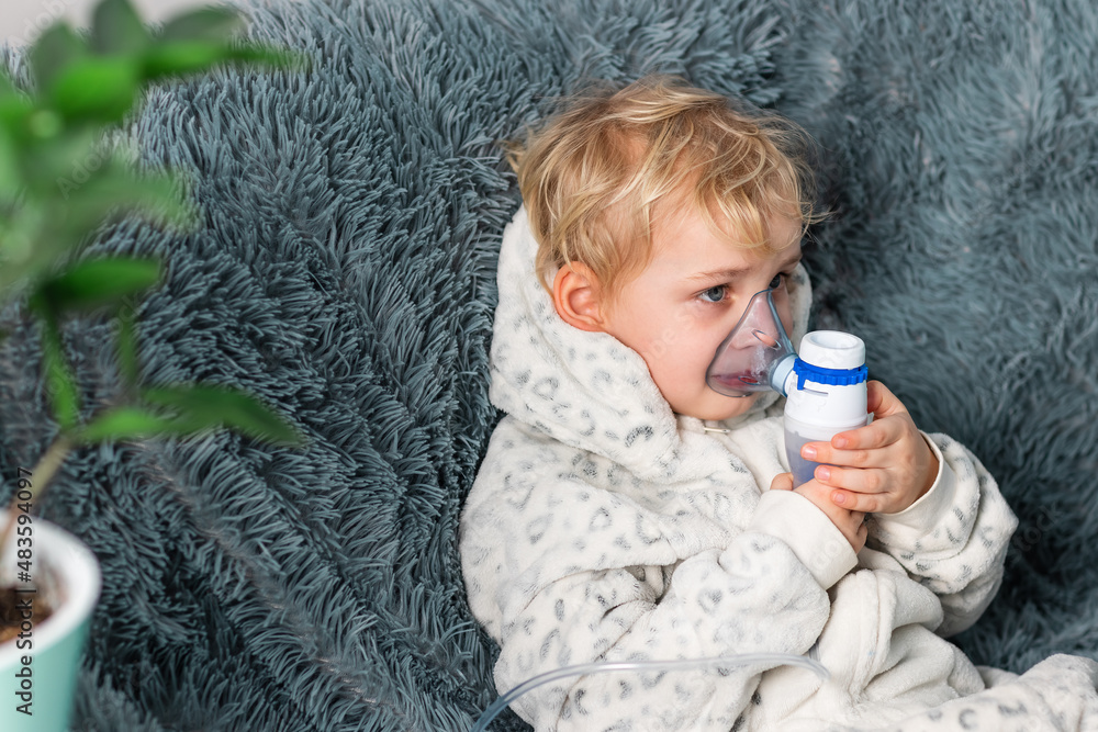 Cute baby boy makes inhalation with a nebulizer equipment. Sick child ...