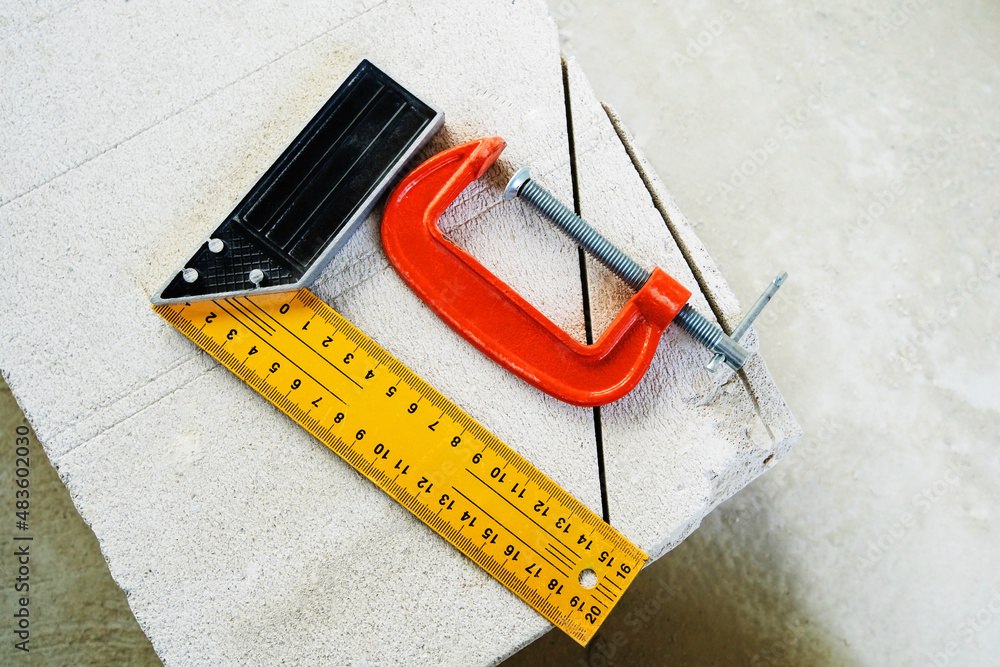 Charcoal ruler and clamp lie on a concrete block. Construction tools ...