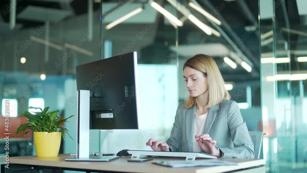 Female office worker in suit working at computer pc in front of monitor ...