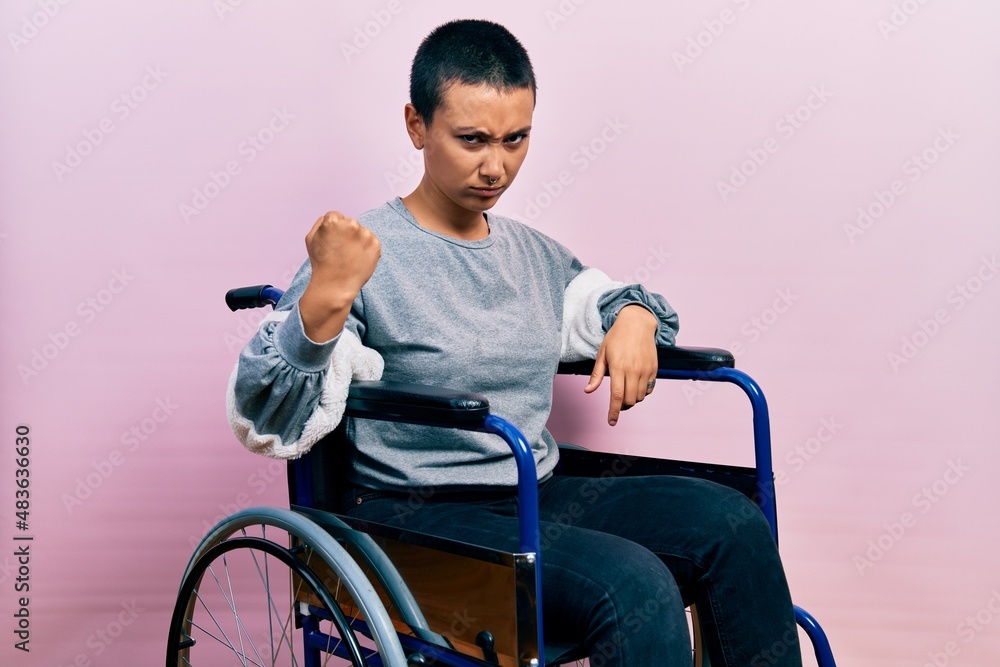 Beautiful hispanic woman with short hair sitting on wheelchair angry ...