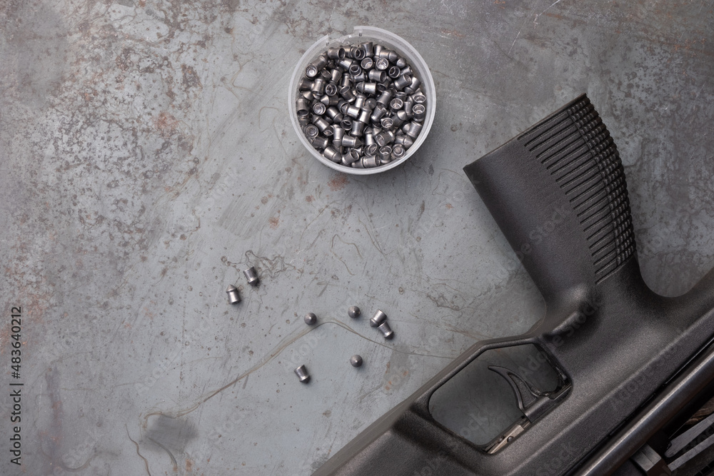 pneumatic shooting.an air rifle and bullets on a steel table. A black ...