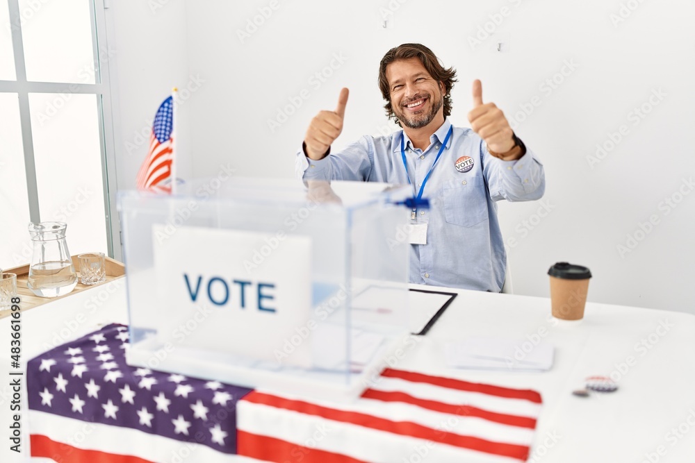 Handsome middle age man sitting at voting stand approving doing ...