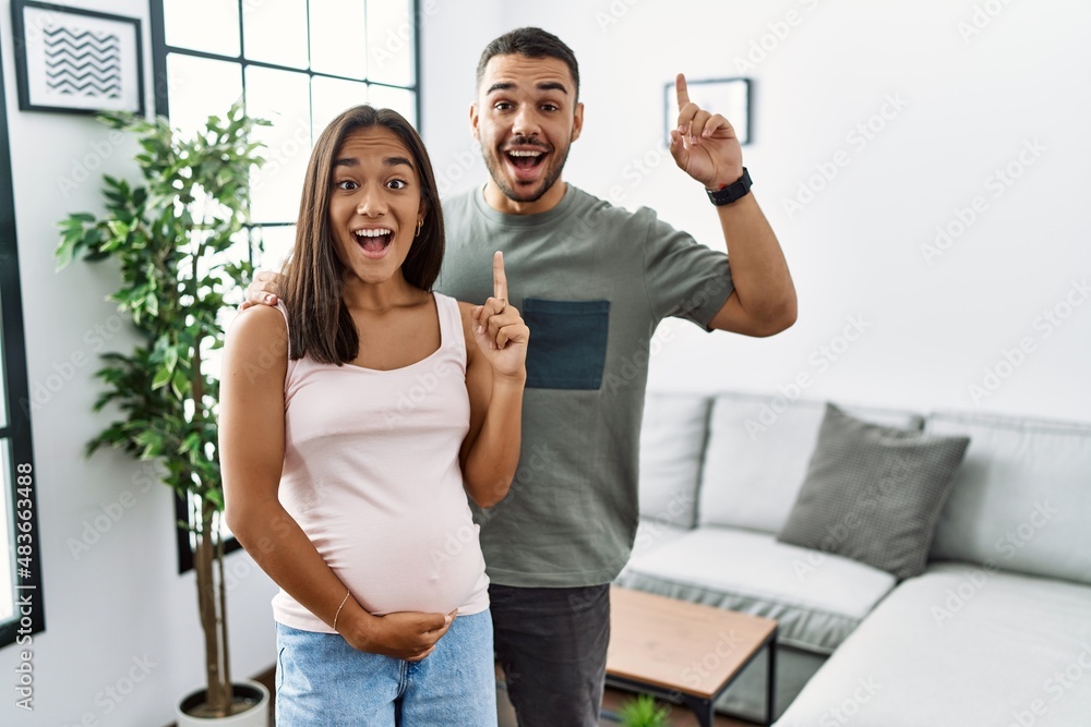 Young interracial couple expecting a baby, touching pregnant belly ...