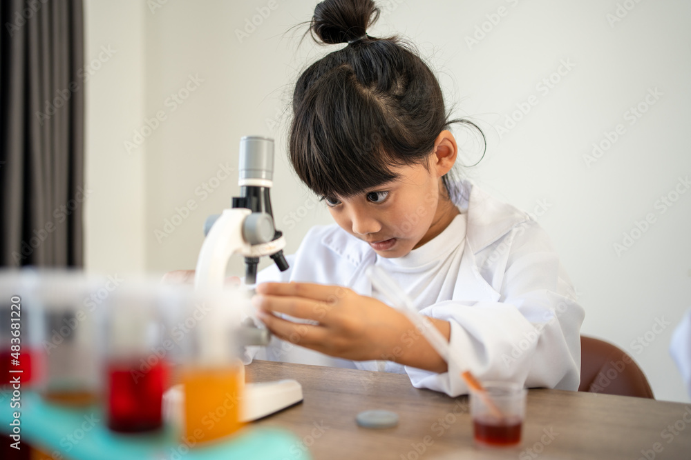 Asian children in lab coat using a microscope for a science experiment ...