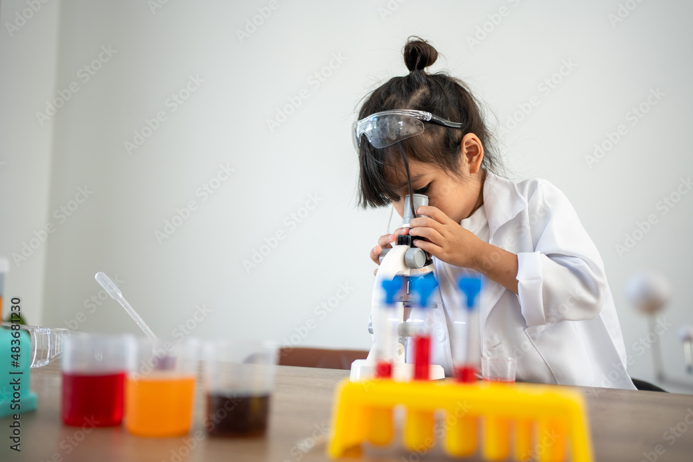 Asian children in lab coat using a microscope for a science experiment ...