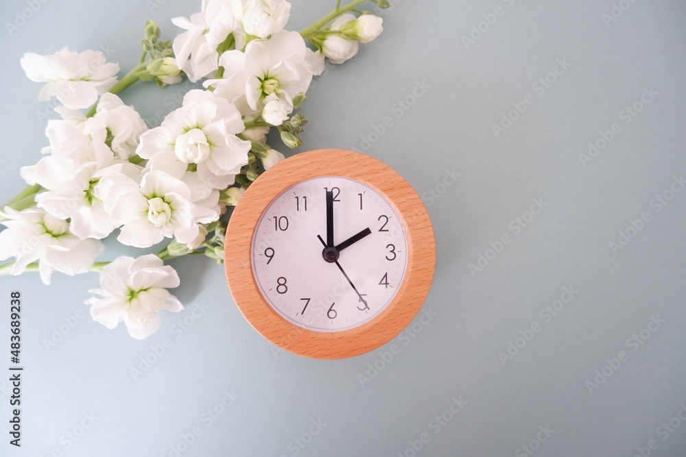 Spring forward concept background. spring flowers and a clock on pale ...