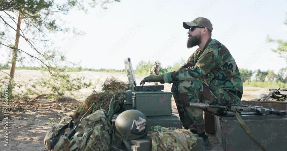 Army commander sits behind computer in field and creates reports to be ...