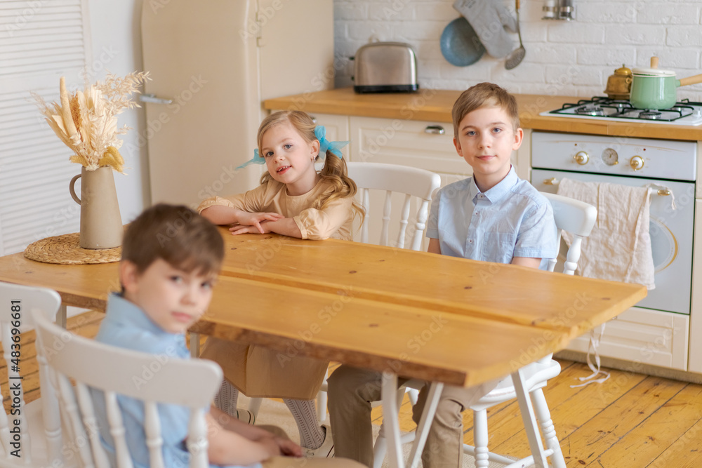 Children sit at table in kitchen and wait for their parents to make ...