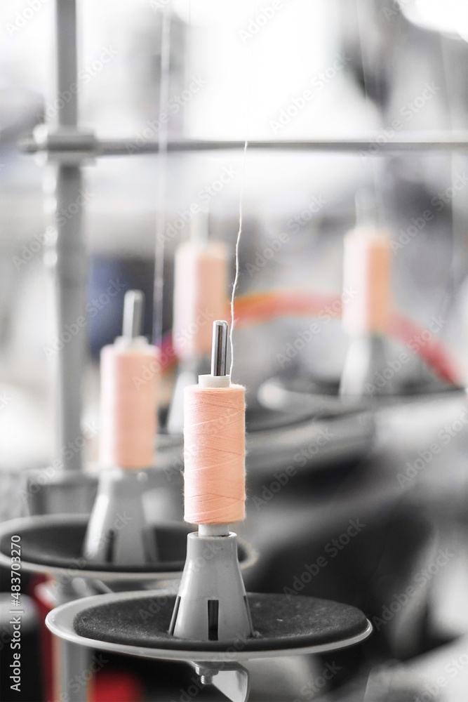 The reel holder on the sewing machine. Four small reels with peach ...