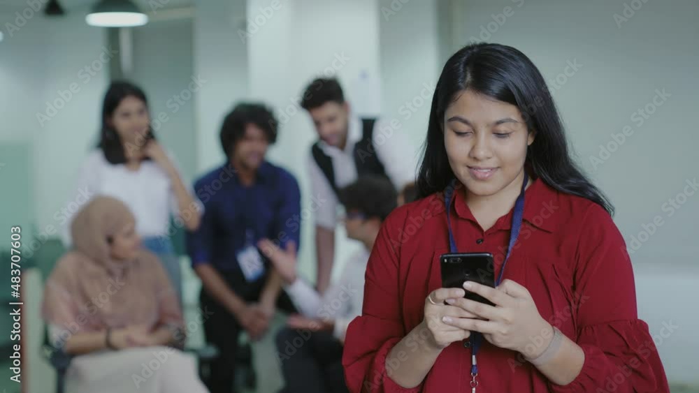 Young Indian woman standing office room and chatting and texting on ...