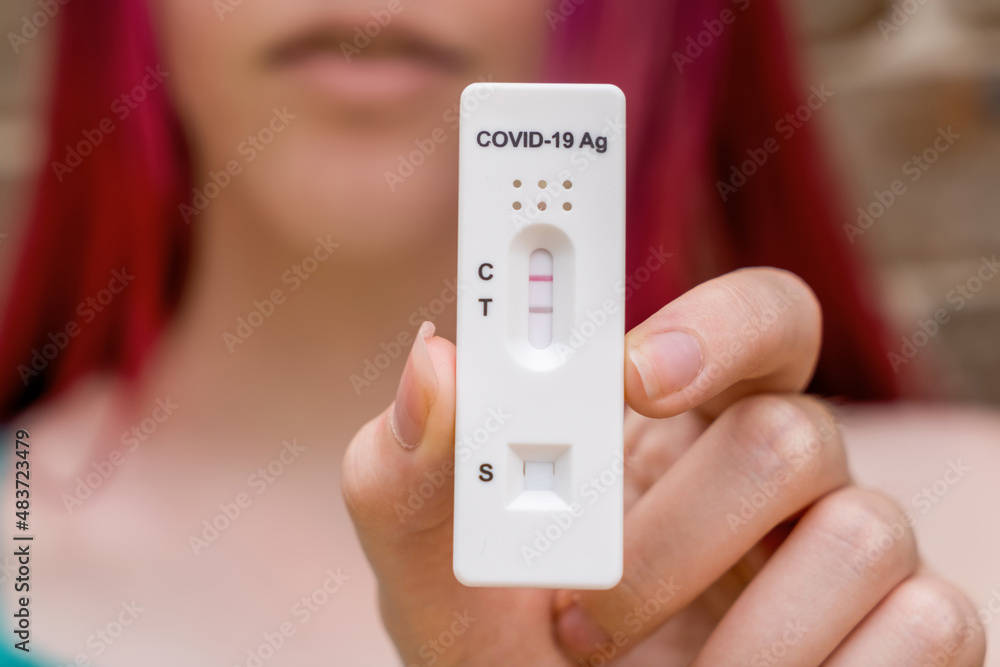 Teenage girl holding Covid-19 rapid antigen test cassette with positive ...