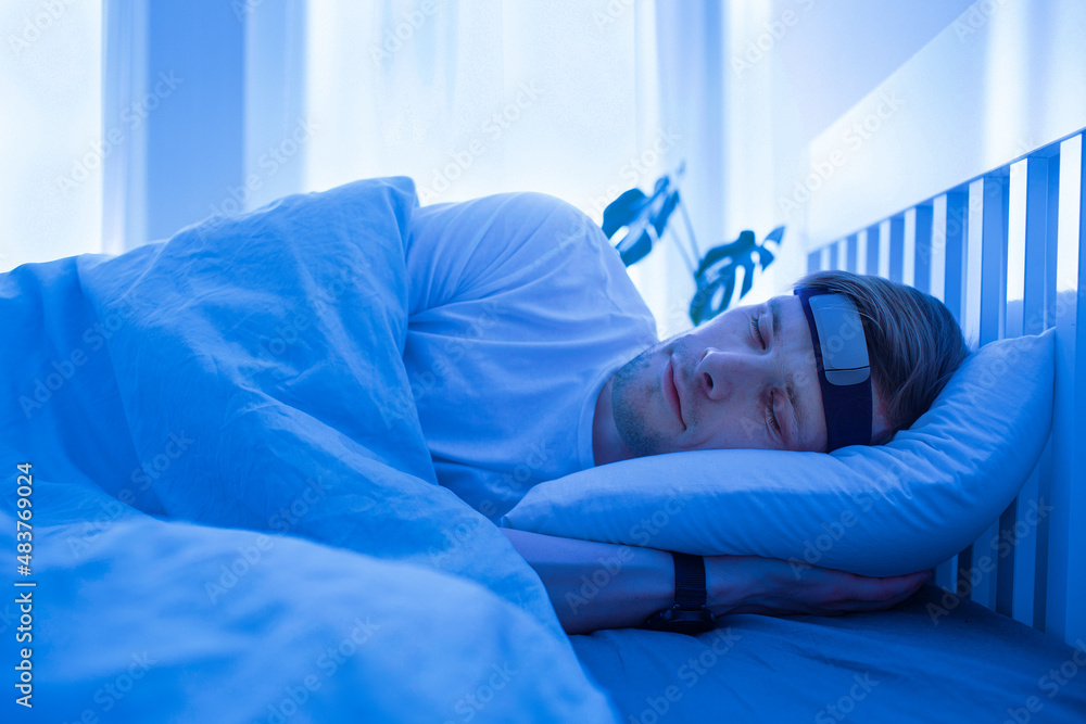Man sleeping on bed with smart sleep headband. Smart sleep tracker ...
