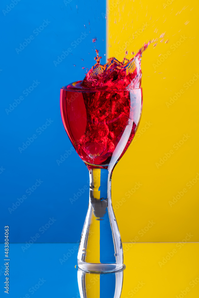 A vertical photograph of a red cherry being dropped into a cocktail ...