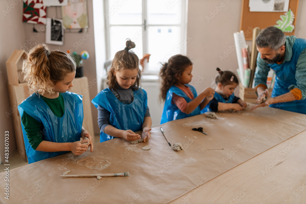 Group of little kids with teacher working with pottery clay during ...