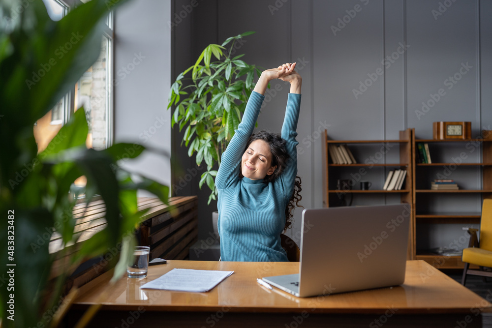 Happy businesswoman warming up body and muscles at workplace, feeling ...
