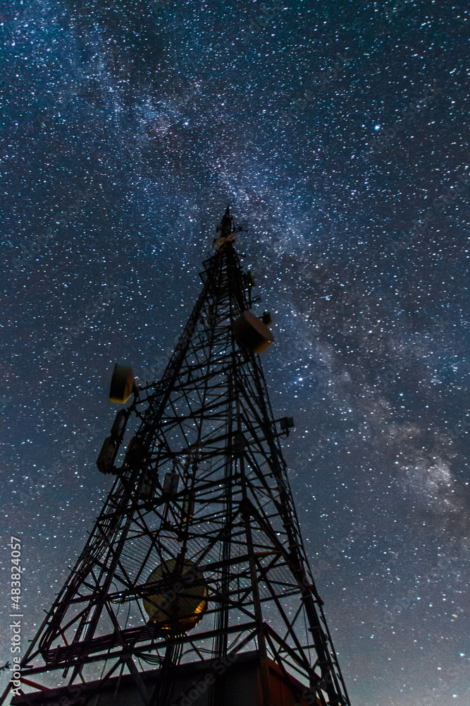 Telecommunication mast pointing into the night sky with the milky way ...