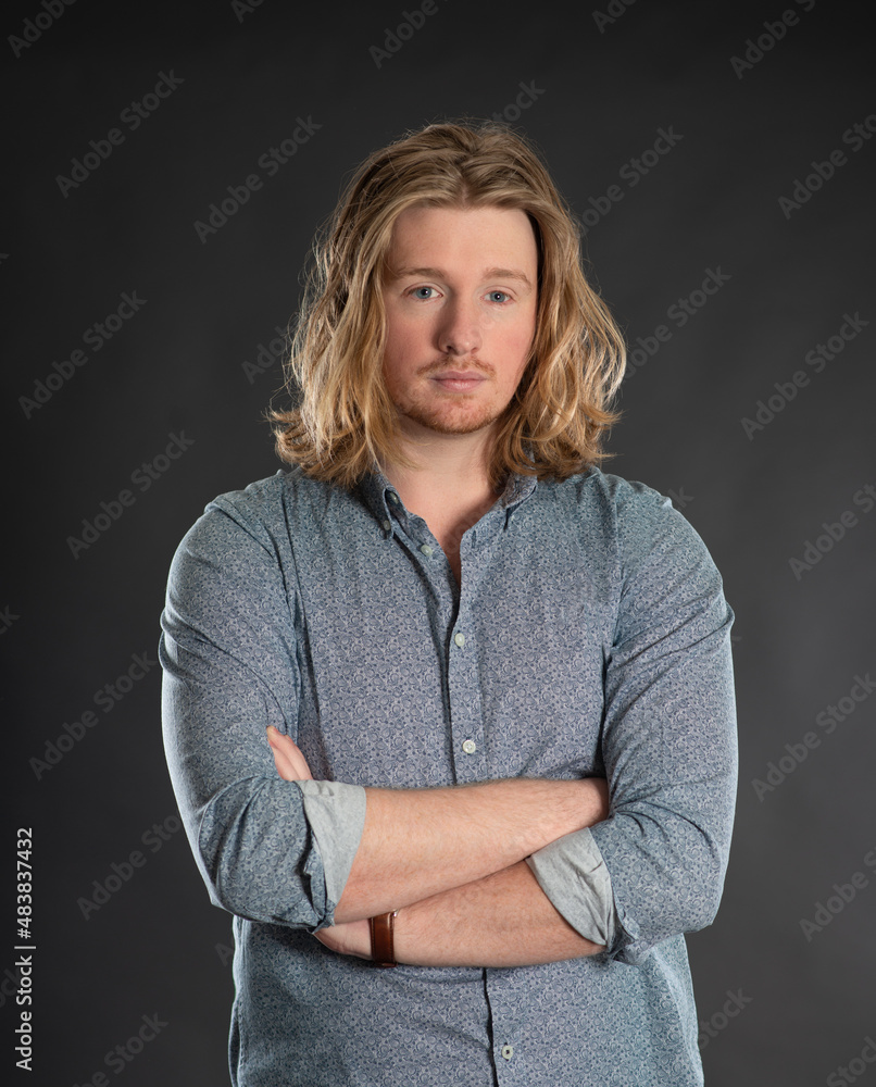Sexy blonde long haired male model arms crossed isolated on black ...
