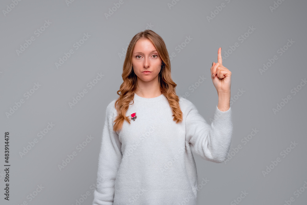 Serious blonde woman pointing finger up, scolding or telling off ...