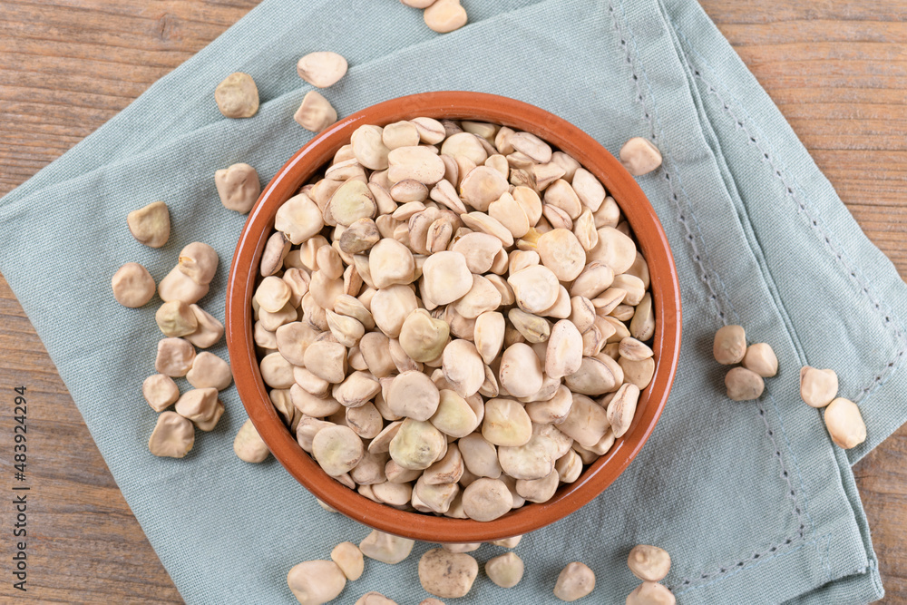 Cicerchia or indian pea on a clay bowl with napkin on natural wooden ...