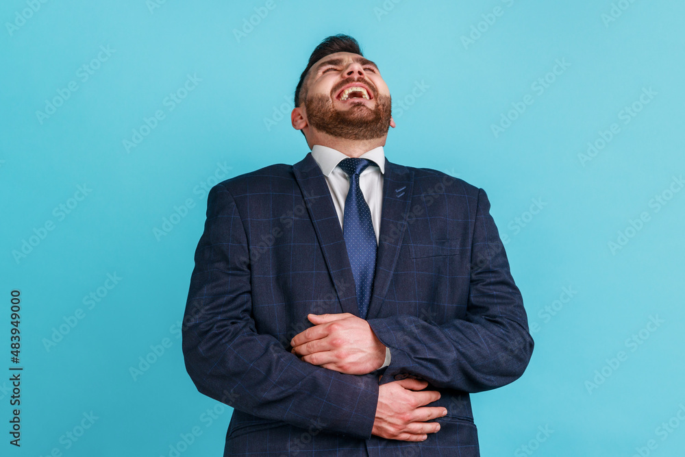 Positive bearded man wearing official style suit holding his belly and ...