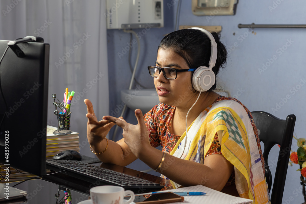 Indian woman in saree working on computer and talking over internet ...