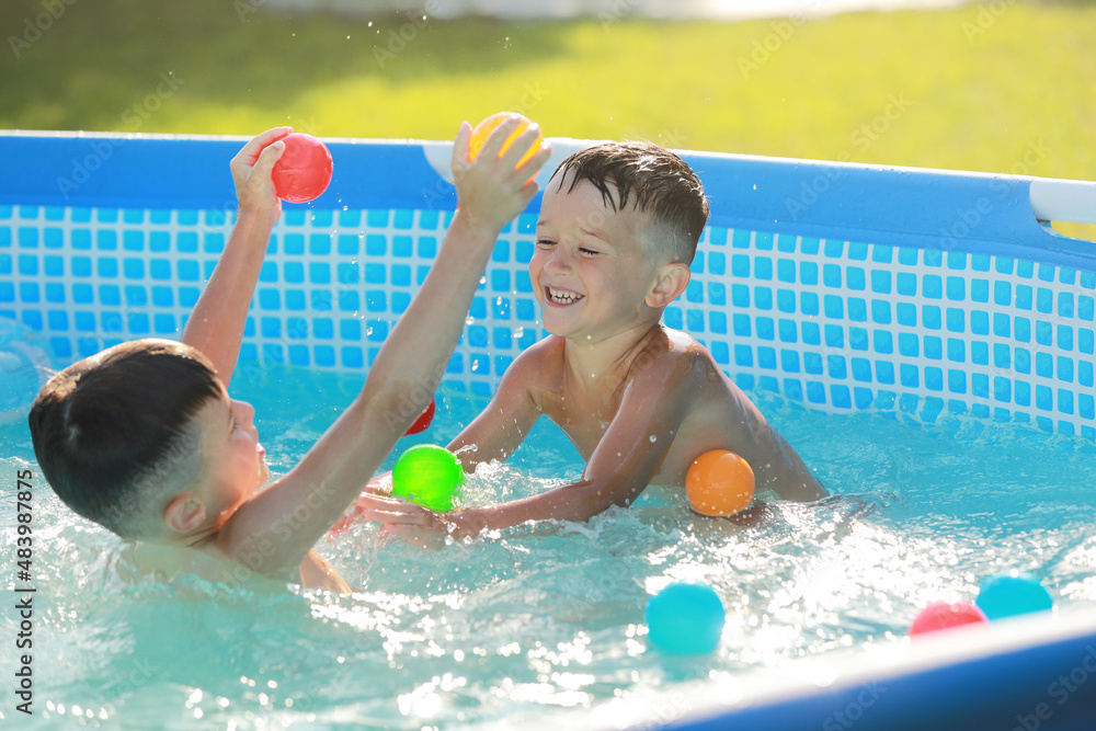 two smiling boys are playing in swimming pool. Summer vacation or ...