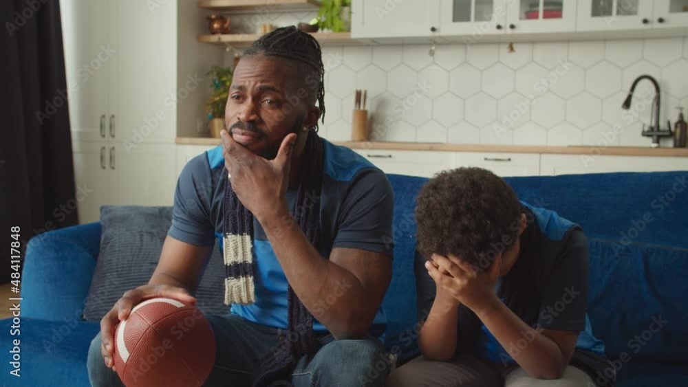 Emotional black father with American football ball and lovely school ...