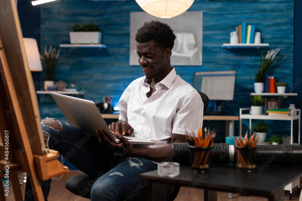 Young artist holding laptop computer searching for draw inspiration ...