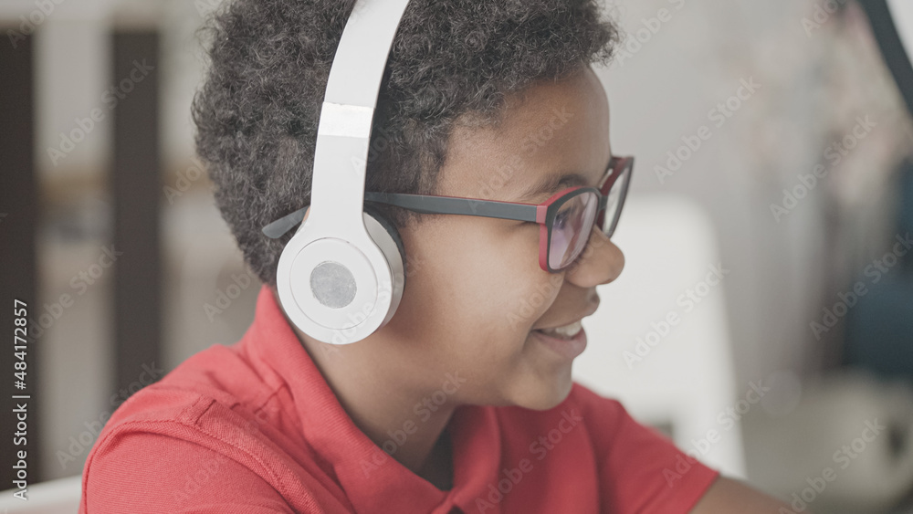 Cute black boy learning foreign language online, wearing headphones ...