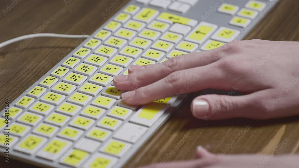 Close-up of a computer keyboard with braille. A blind girl is typing ...