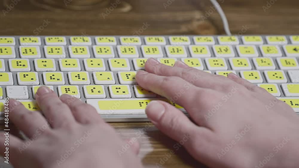 Close-up of a computer keyboard with braille. A blind girl is typing ...