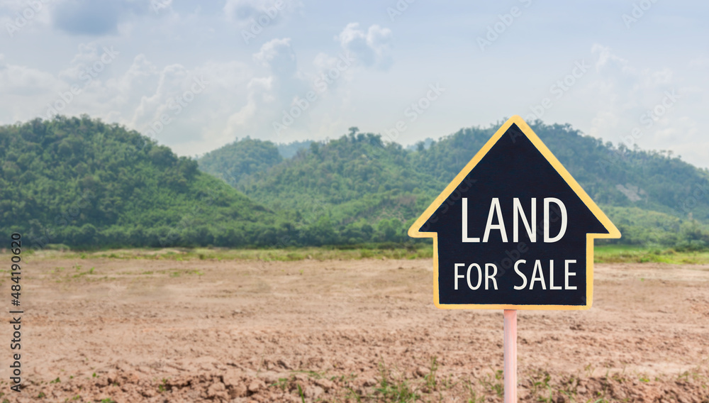 land for sale sign against trimmed lawn background. Empty dry cracked ...