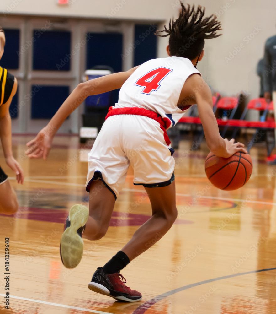 Basketball player dribbling the ball and making a nove on his defender ...