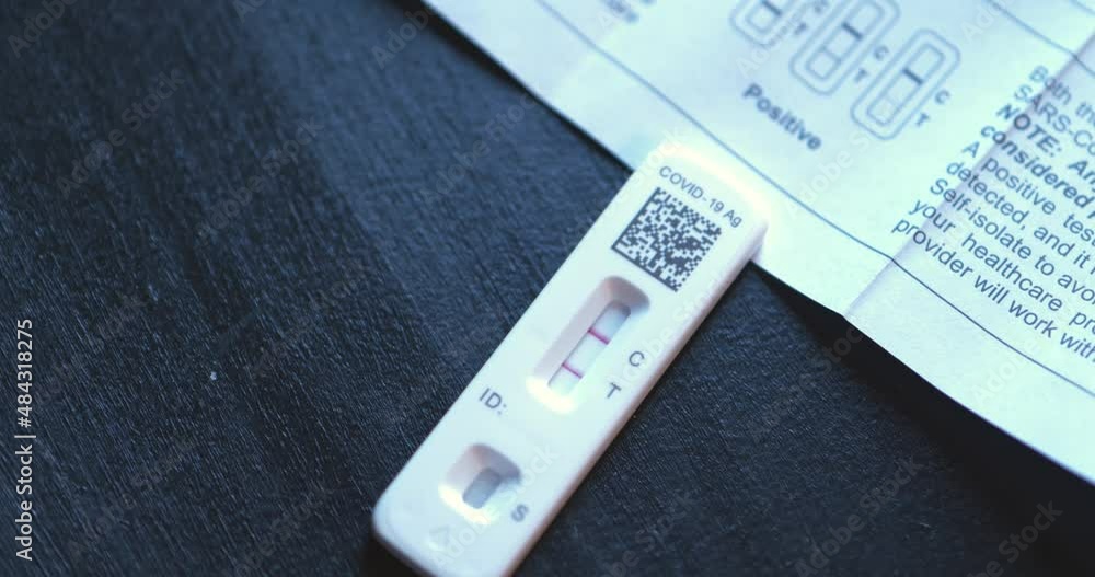 Covid 19 positive at home test kit on black table with instruction book ...