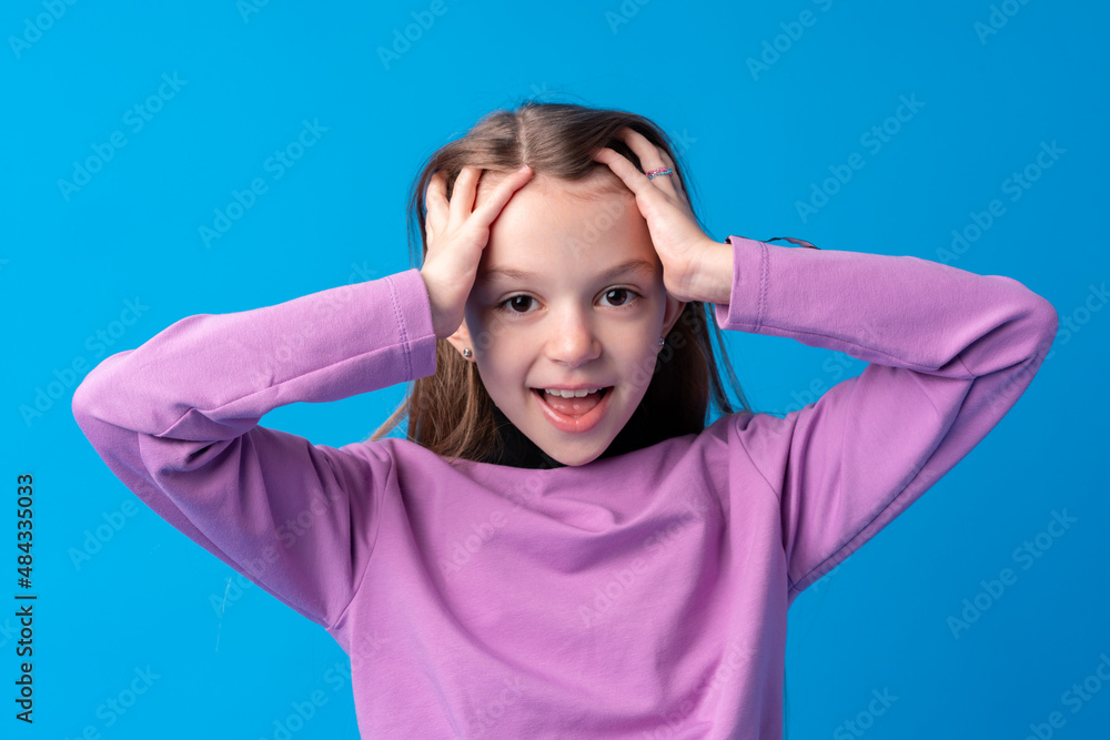 Shocked little girl looking with amazement on blue background Stock ...