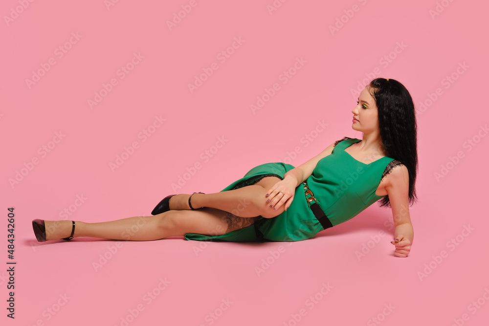 Young woman is lying on the floor with her leg pulled up over pink ...