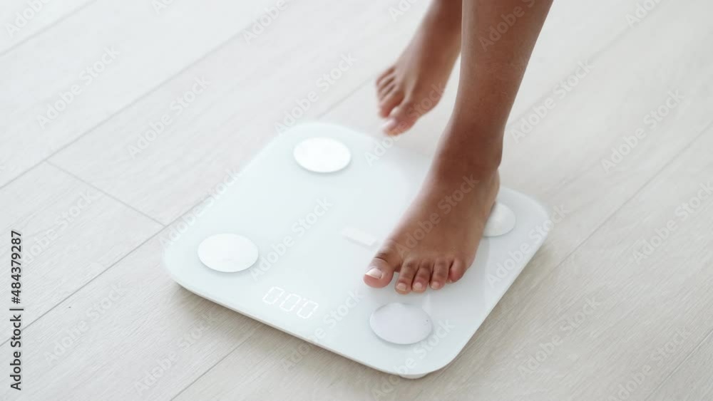 Legs of black girl standing on scale to measure weight. African ...