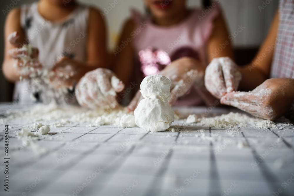 Funny children play with artificial snow at home in the kitchen ...