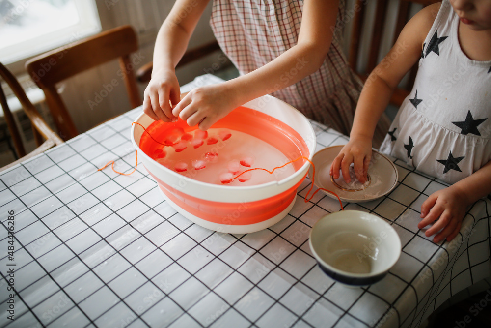 Funny children play with hearts and water at home in the kitchen ...