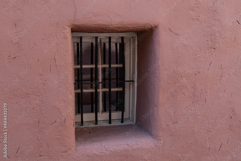 Angled view of an adobe building wall and window, deep inset with ...